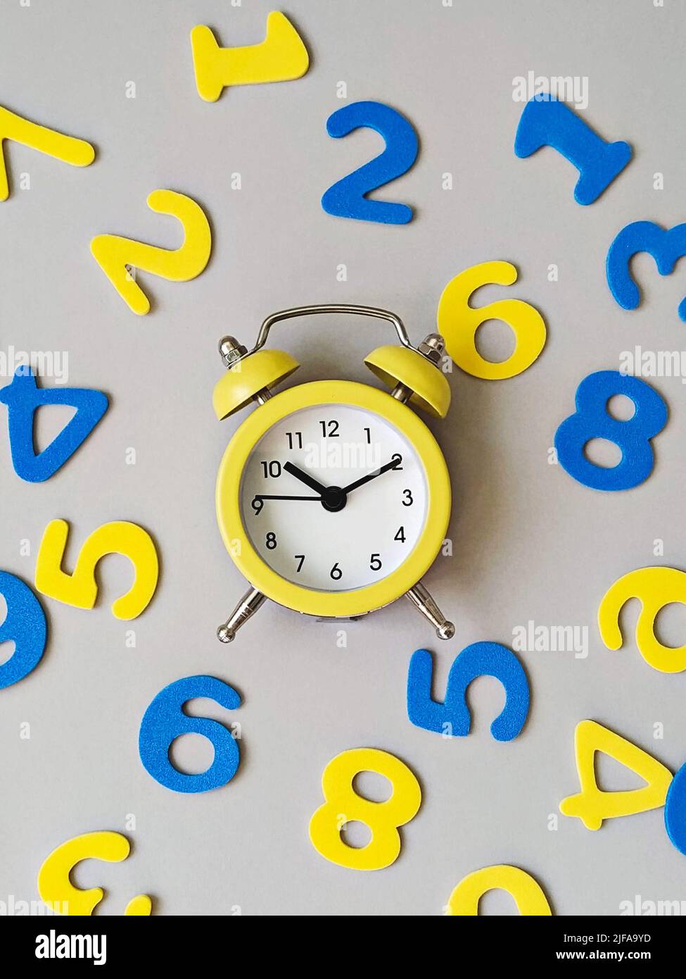 Illuminated yellow alarm clock on ultimate gray background with blue ...