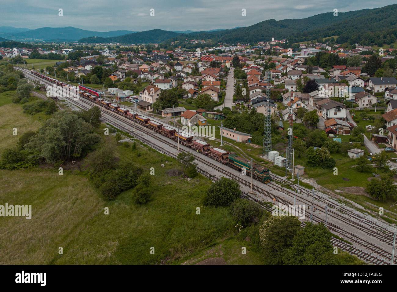 Long diesel freight train loaded with hopper cars full of gravel or ...