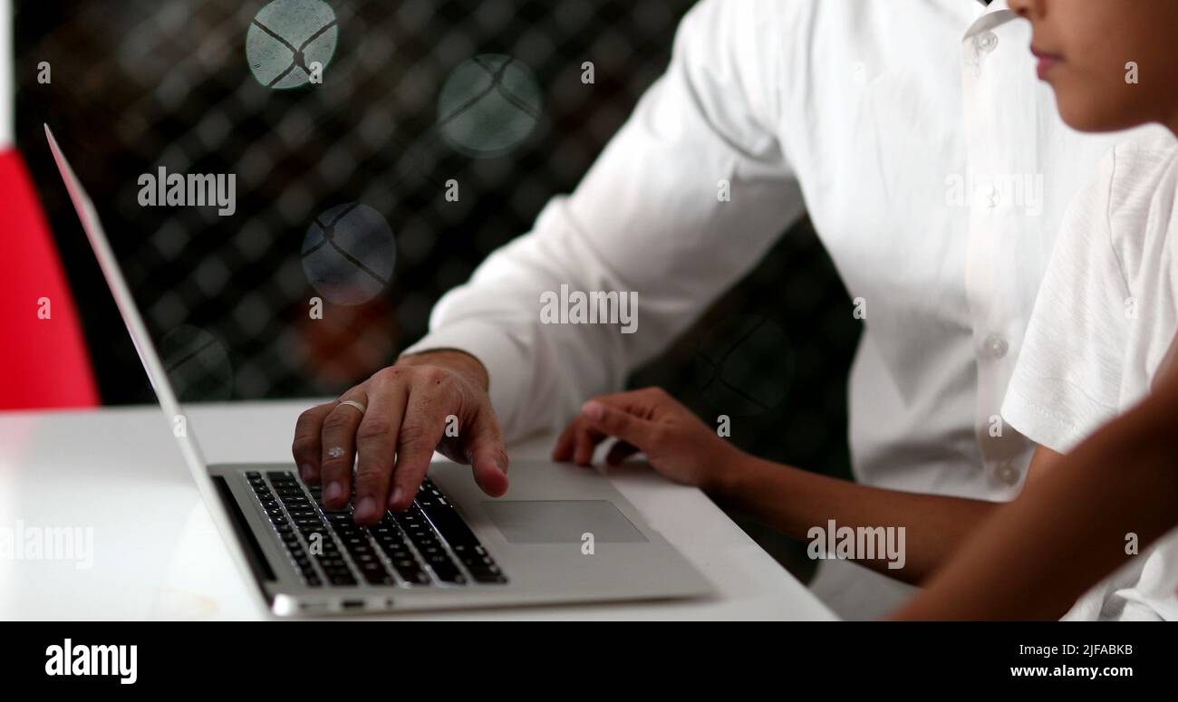 Candid parent and child together in front of computer doing homework at ...