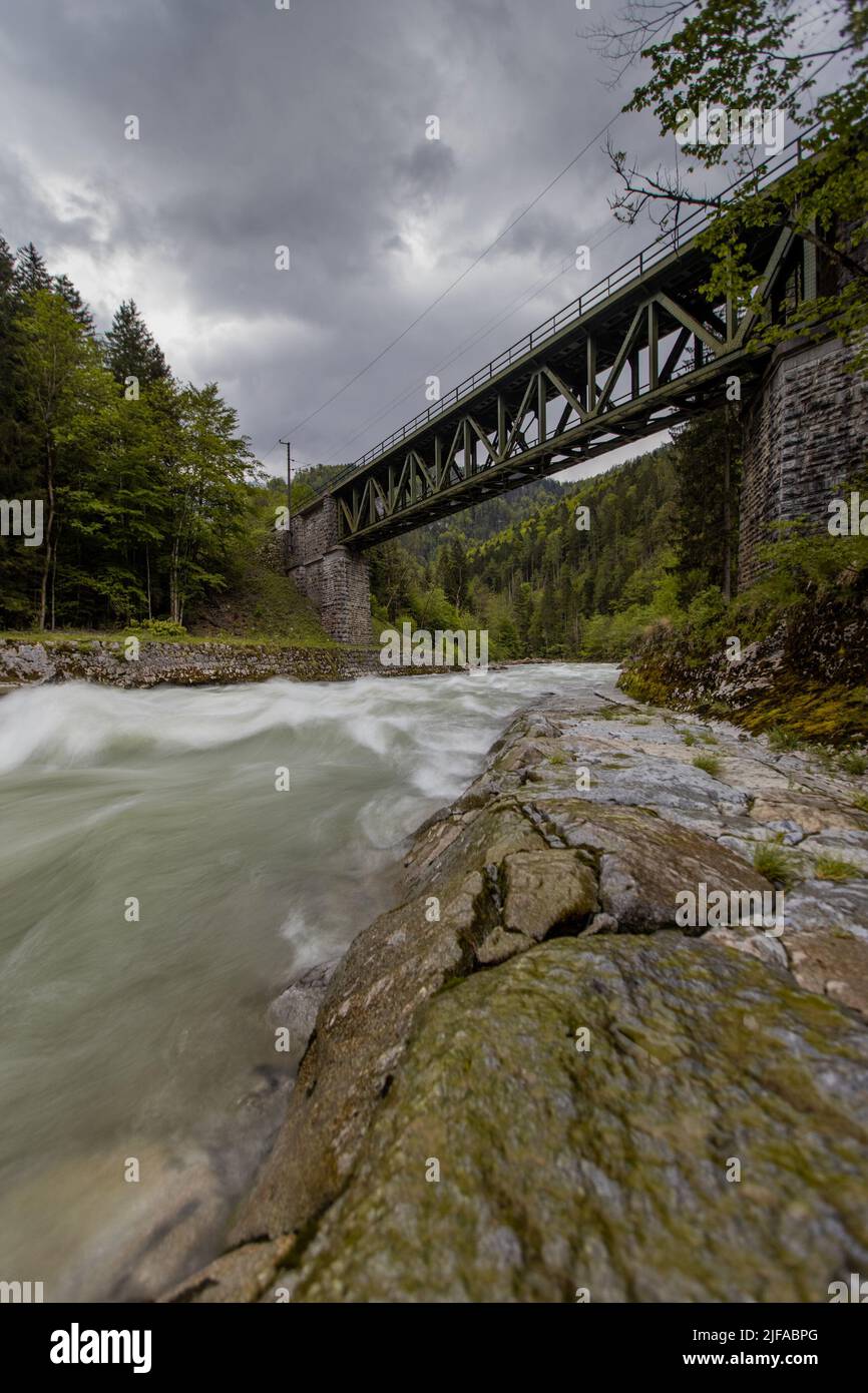 Old green railway bridge over wild river Enns in cloudy weather in ...