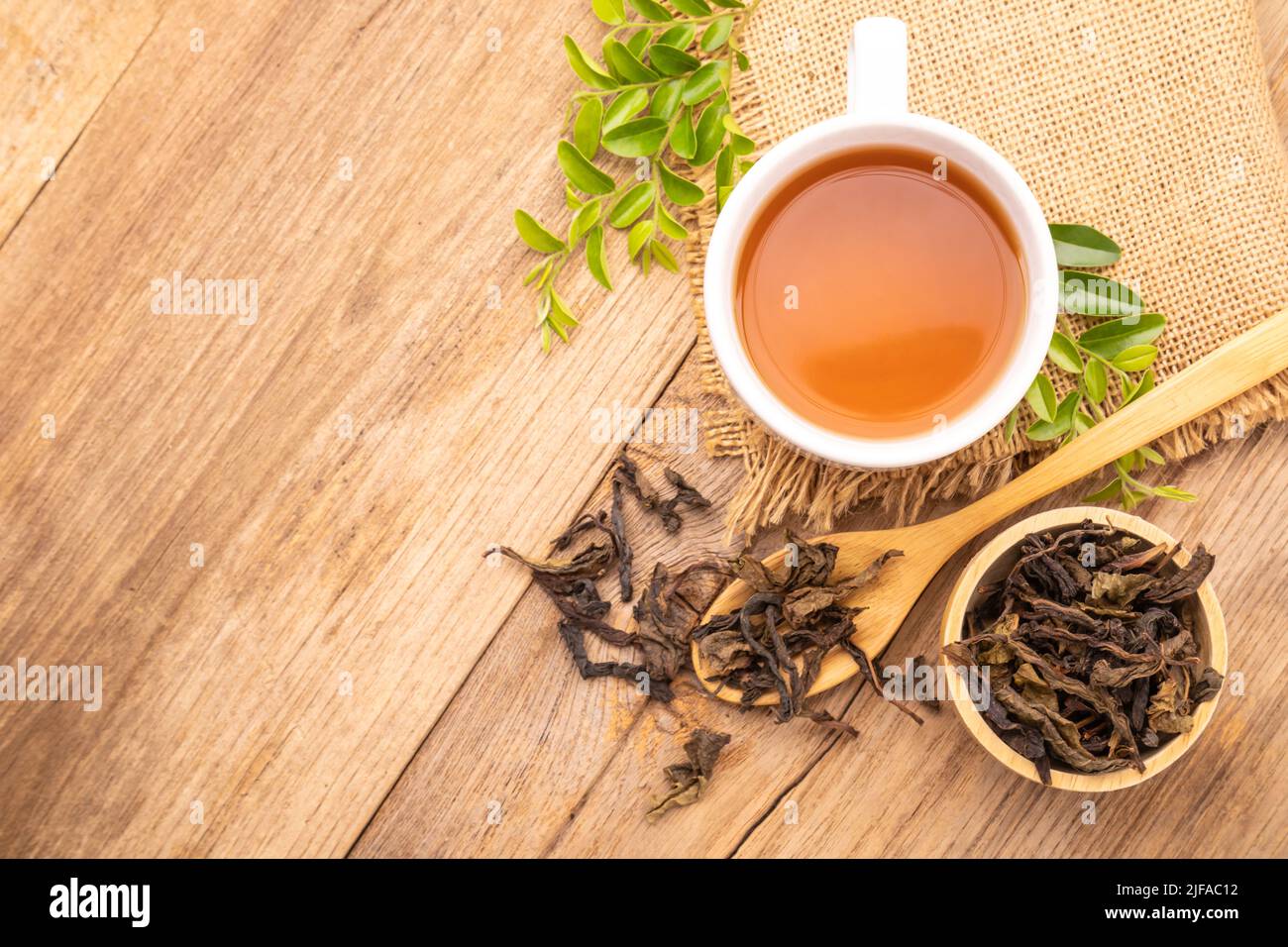 White cup of hot tea and dry tea leaf on wooden table background Stock ...