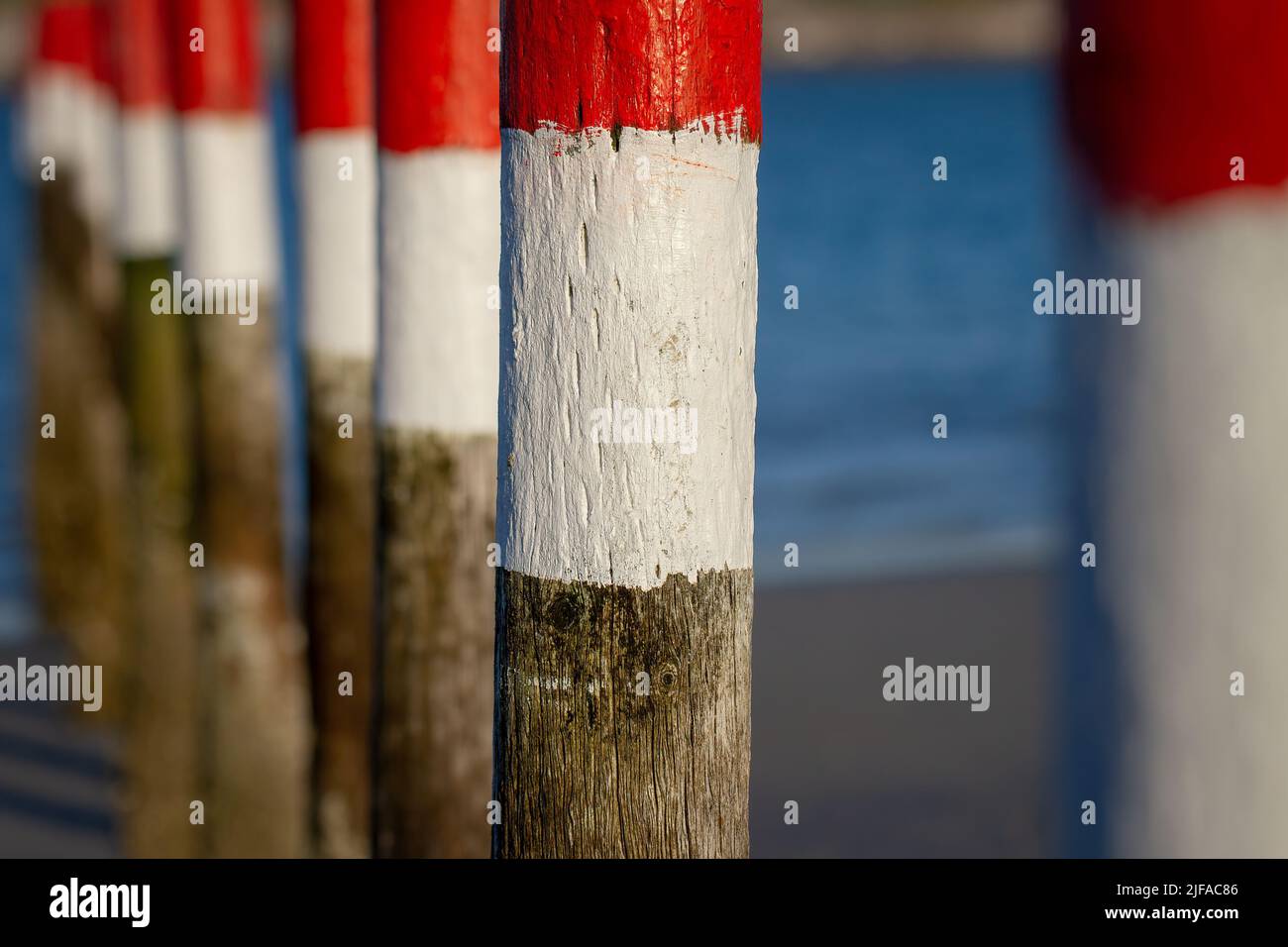 Red and white painted wooden bollard markers in the lagoon Stock Photo ...