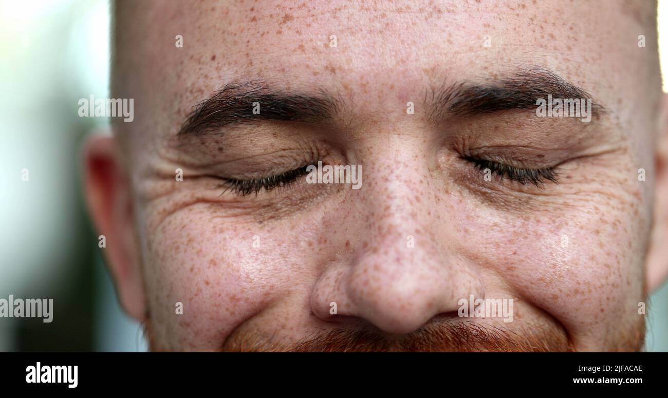 Contemplative young man closing eyes, taking a deep breath, feeling ...