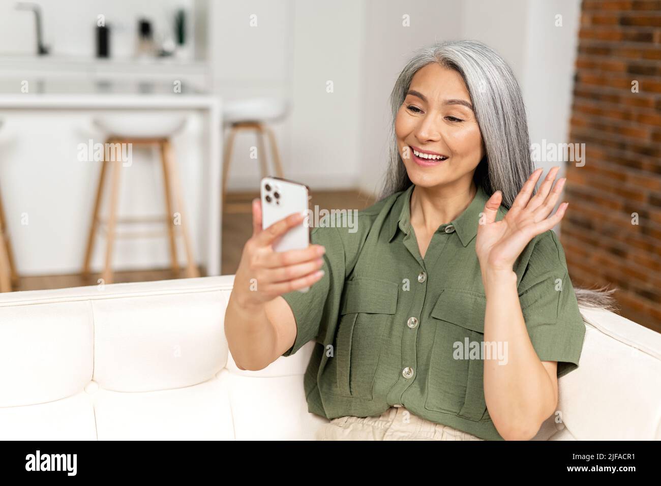 Senior female holding mobile phone and waving hand. Happy smiling ...