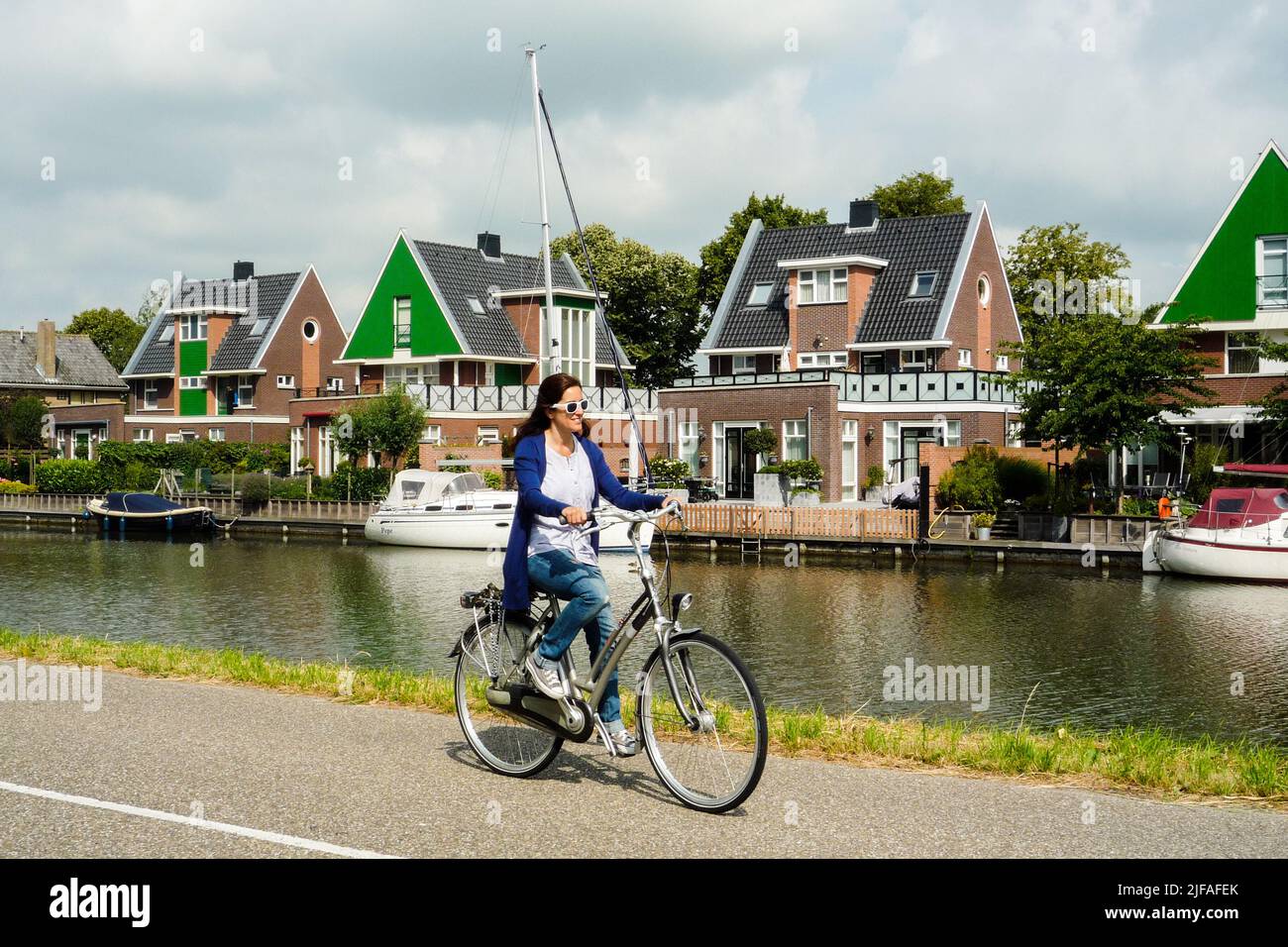 Caucasian woman riding a bike in Volendam, Dutch town on the Markermeer ...