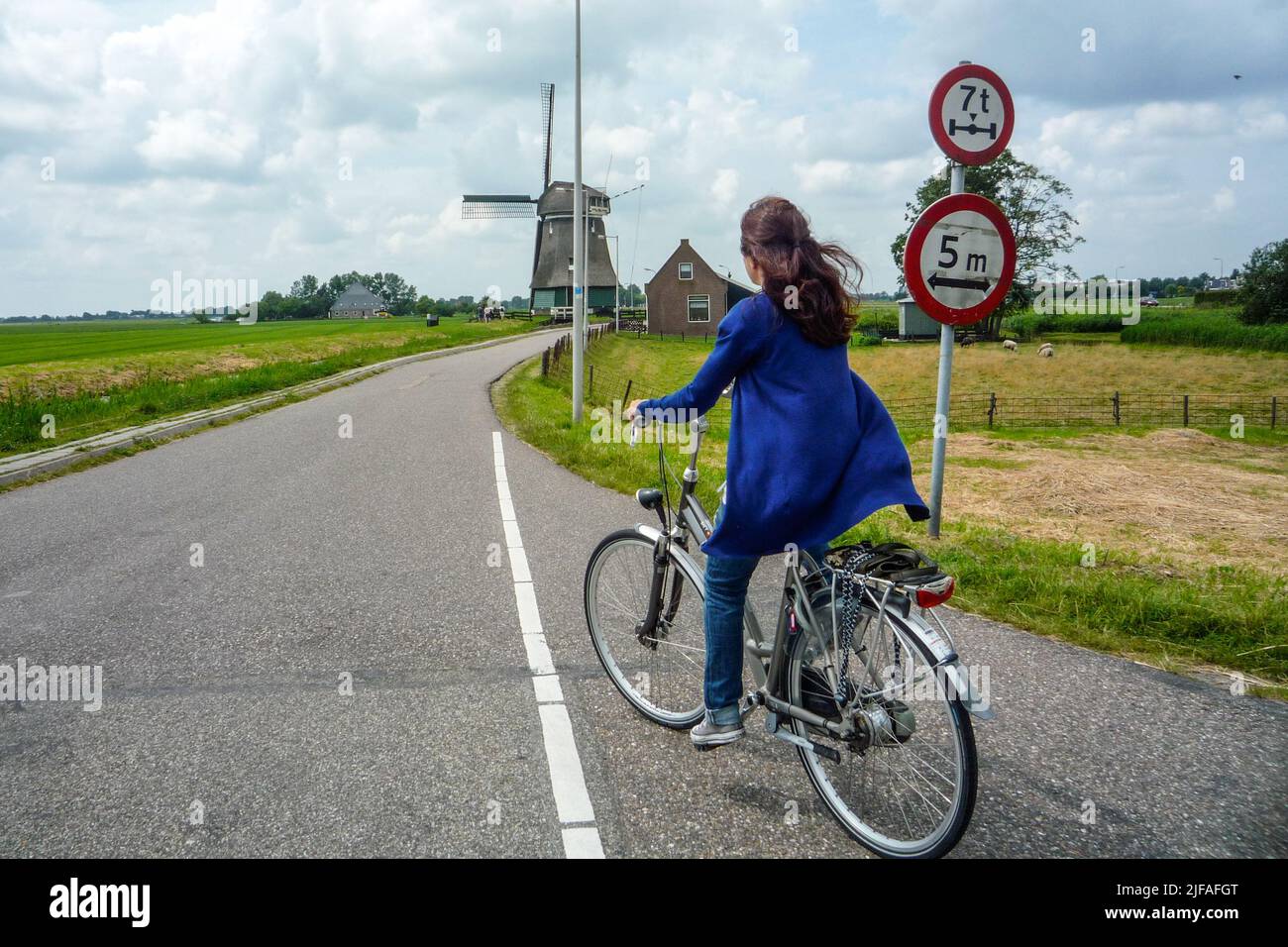 Caucasian woman riding a bike in Volendam, Dutch town on the Markermeer ...