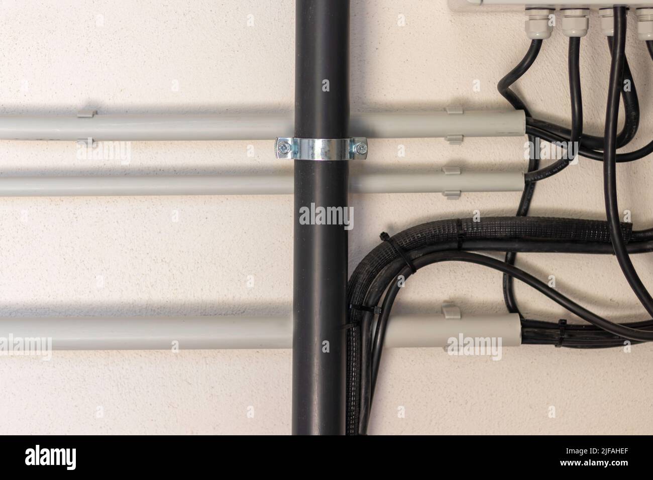Close up view of electrical and plumbing instalation on white wall ...