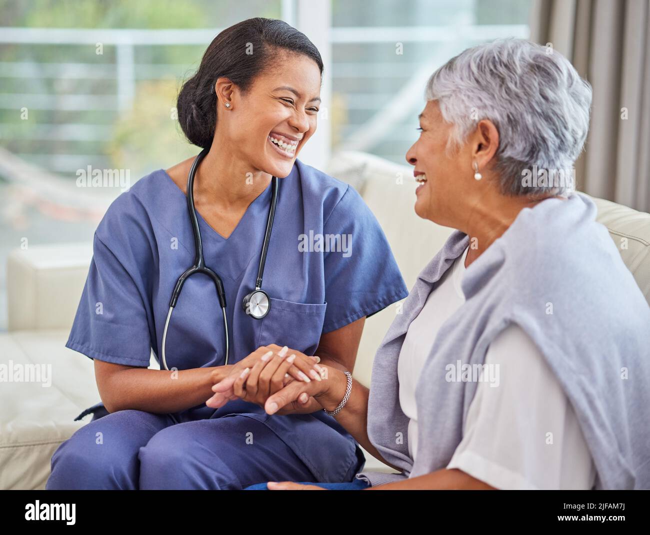A hispanic senior woman in on a cosy sofa and her female nurse in the ...