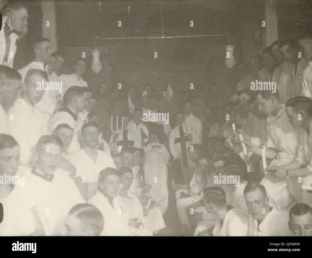 Event with white -clad men, some of whom hold light in their hands ...