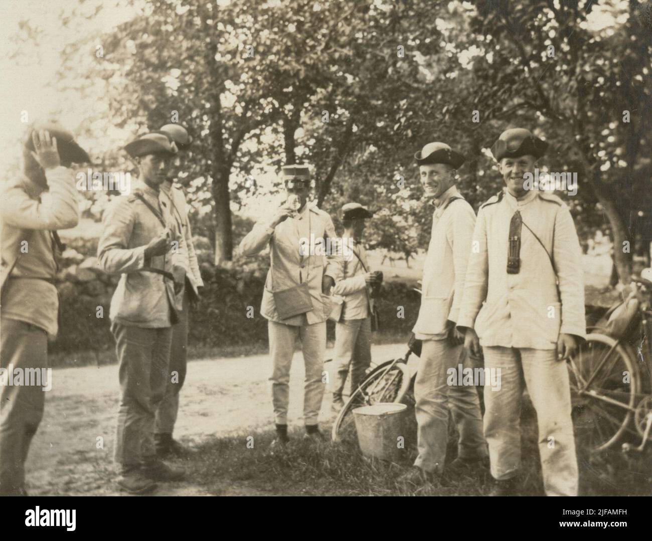 A group of soldiers have a break at a road. The road is lined with a ...
