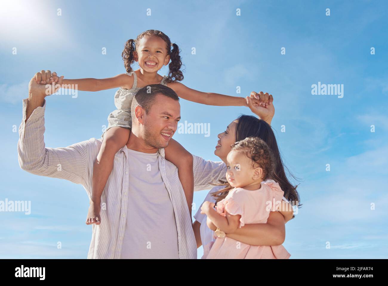 A happy mixed race family of four enjoying fresh air at the beach ...