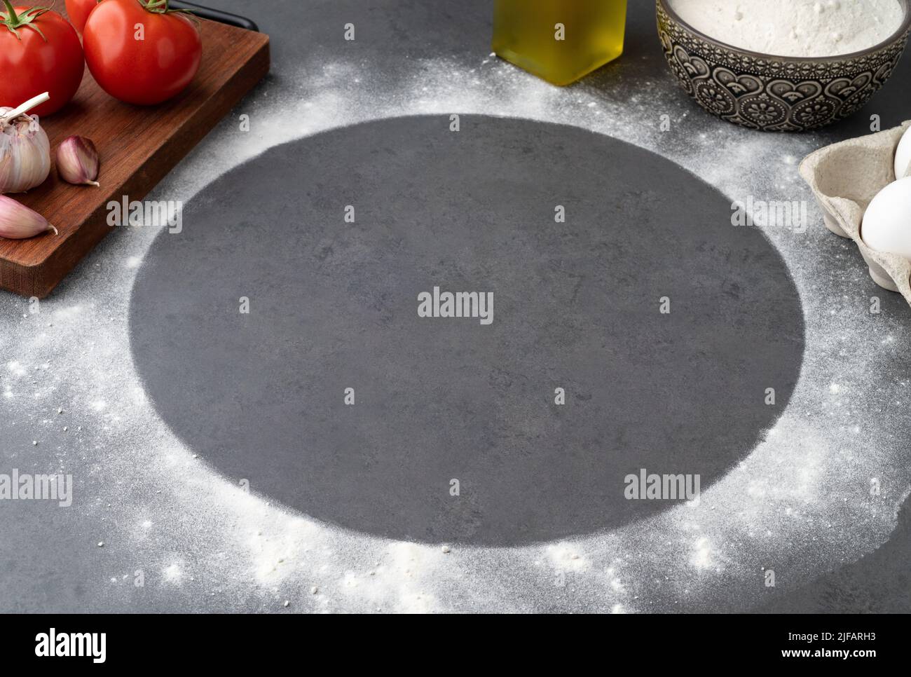 Empty pizza space with tomatoes, eggs and flour over stone background ...