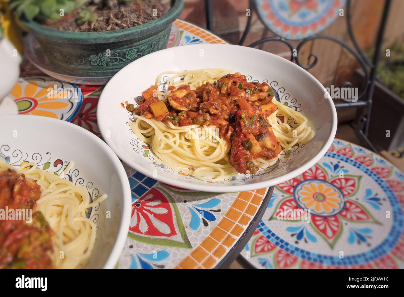 Two pasta dishes on a colourful ceramic table Stock Photo - Alamy