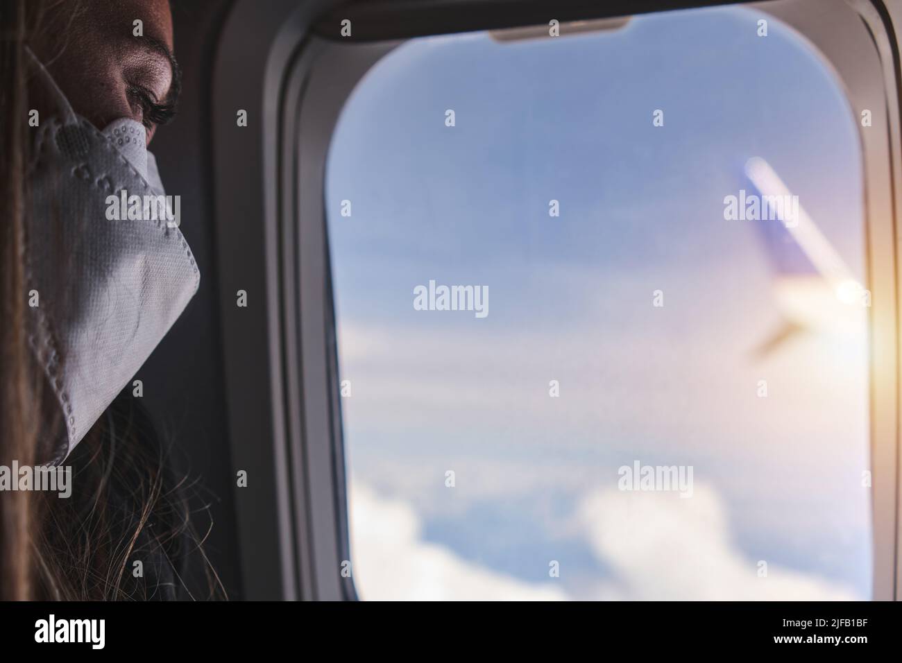 Woman looking at sky with clouds from the airplane window. sunset in ...