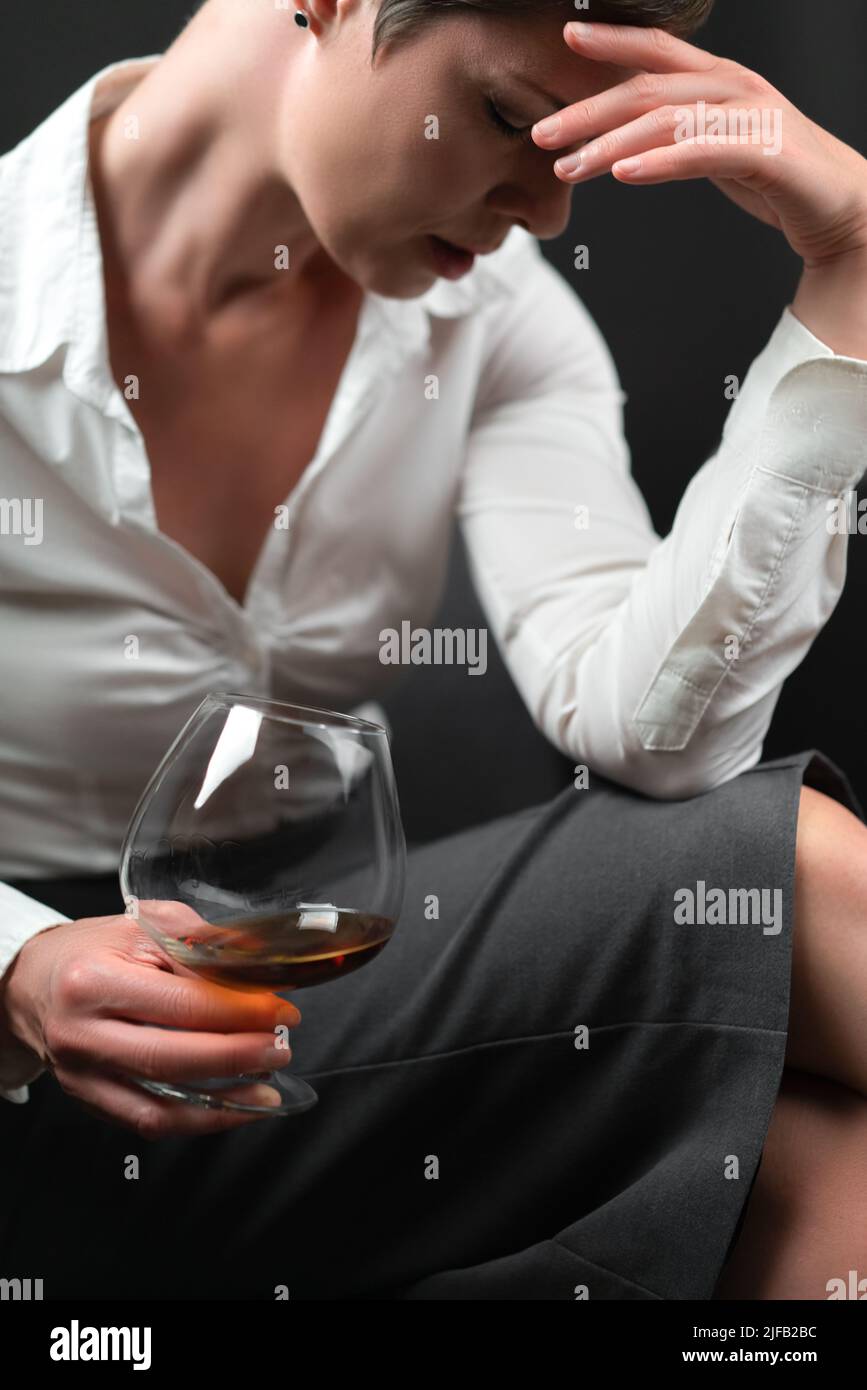 Vertical studio shot of drinking glass filled with alcohol held by ...