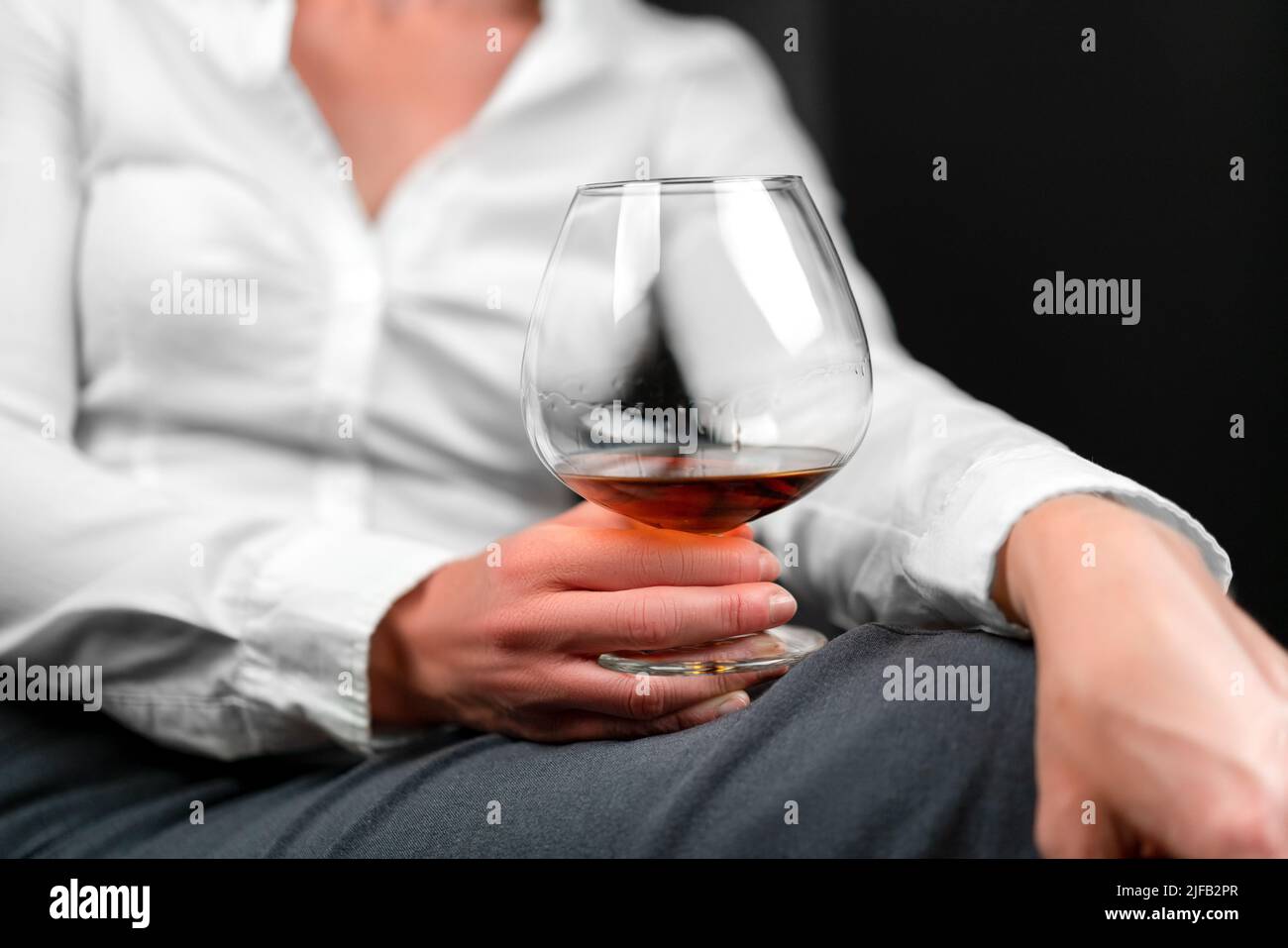 Drinking glass filled with alcohol held by woman in business clothes ...