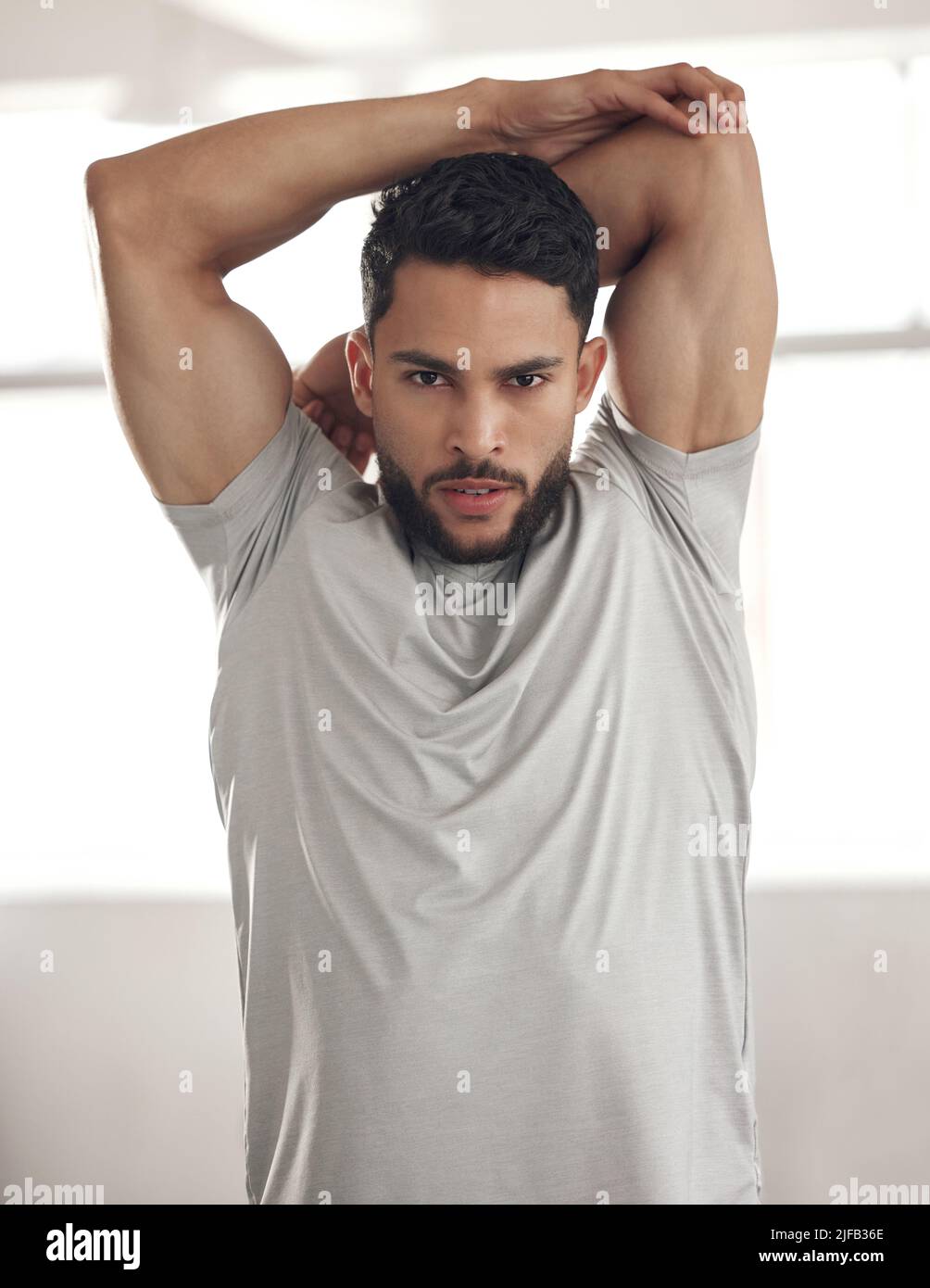 Portrait of one fit young hispanic man stretching arms and shoulders ...