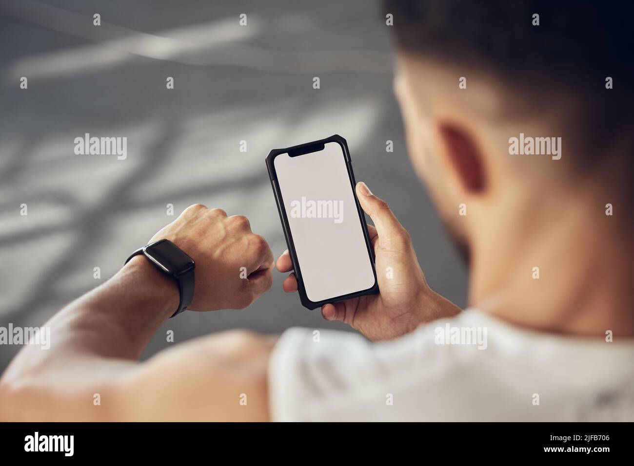 Athlete using their smartphone to track their progress. Fit man using a watch to track workout ...