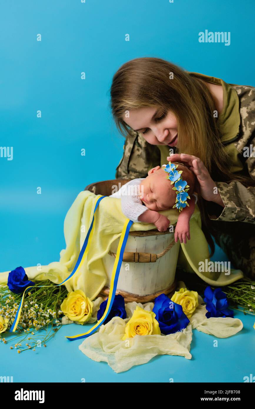 A Ukrainian mother in military uniform with an infant in the colors of ...