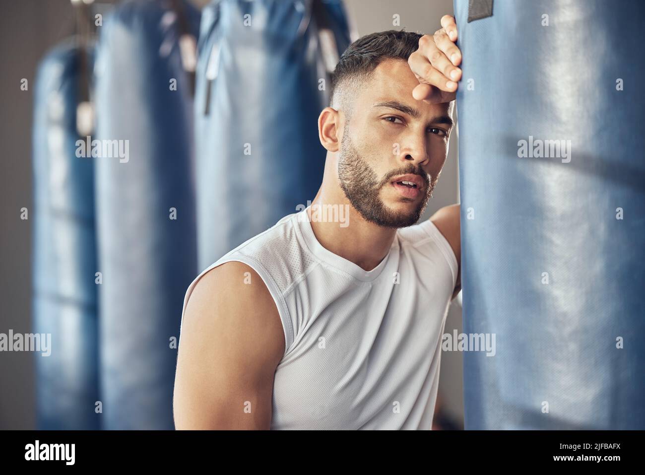 Portrait of tired boxer leaning on punching bag. Exhausted mma fighter ...