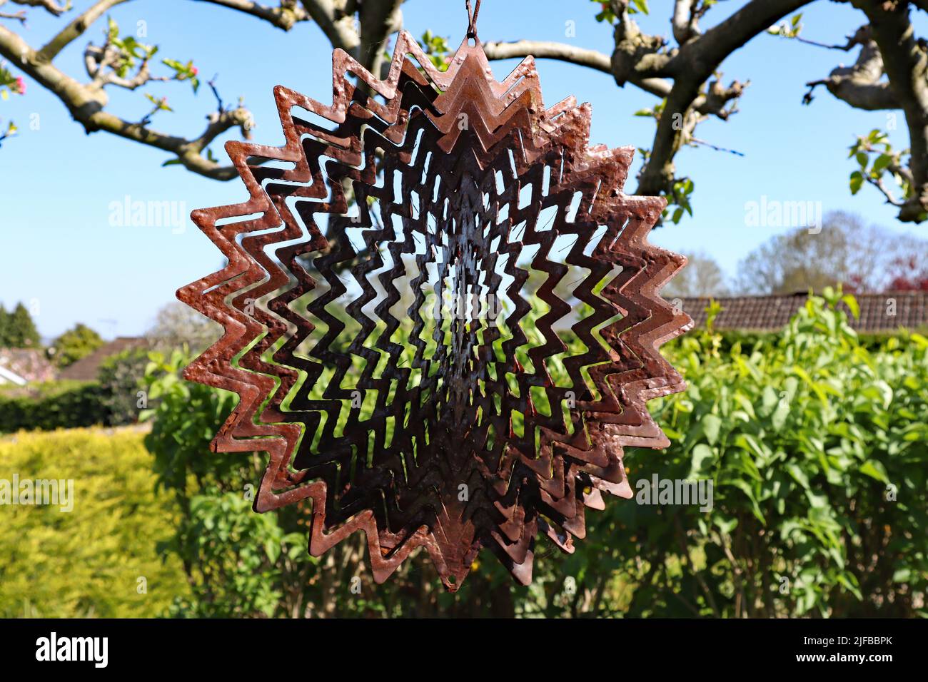 A brown metal ornament in the shape of a spiral star hanging from the ...