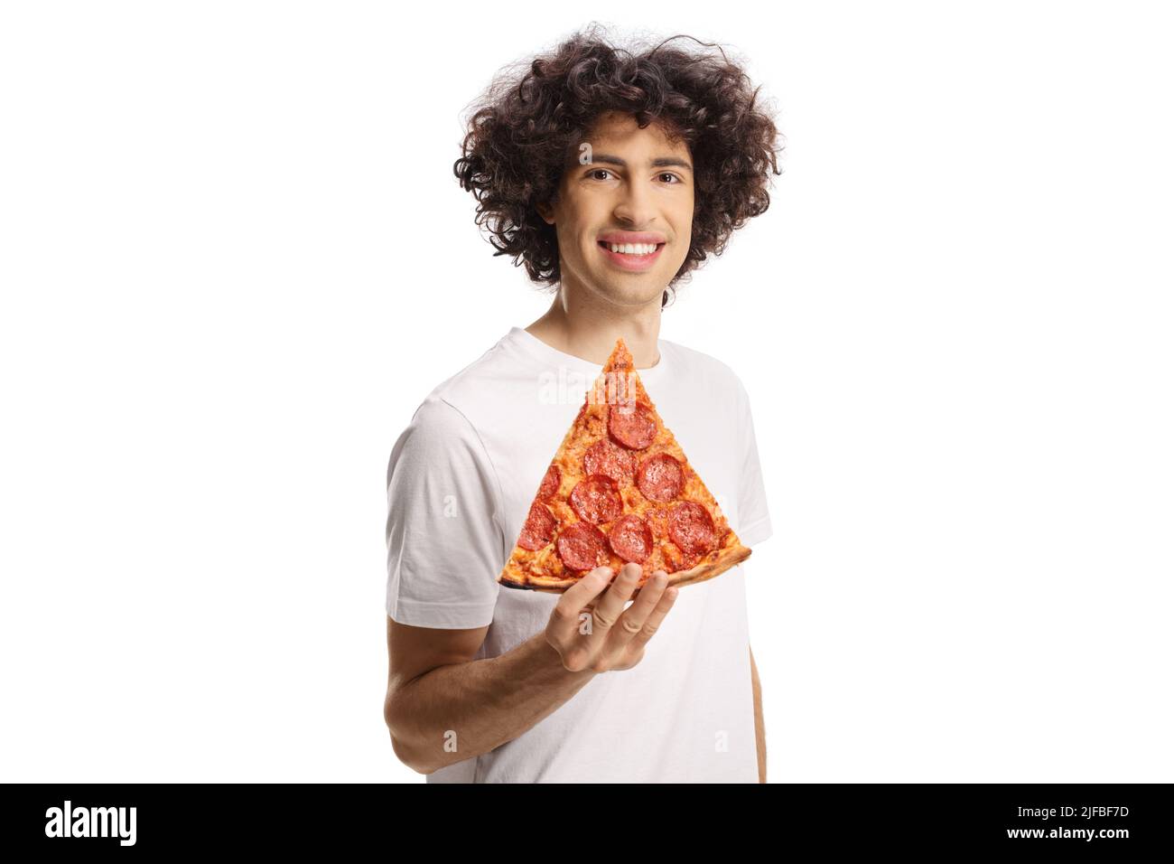 Cheerful young man holding a slice of pepperoni pizza and looking at ...