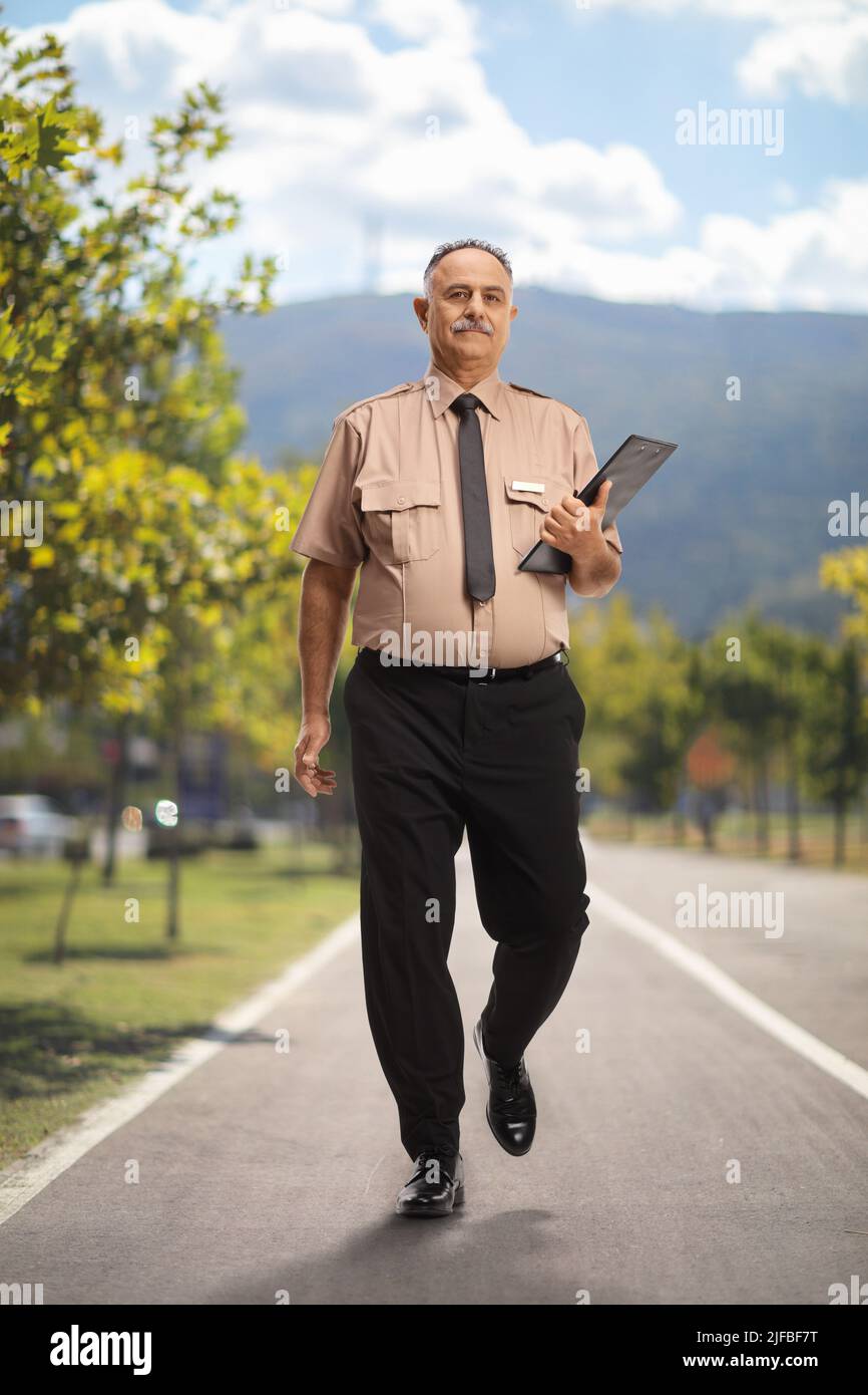 Full length portrait of a security guard walking on a pedestrian lane ...