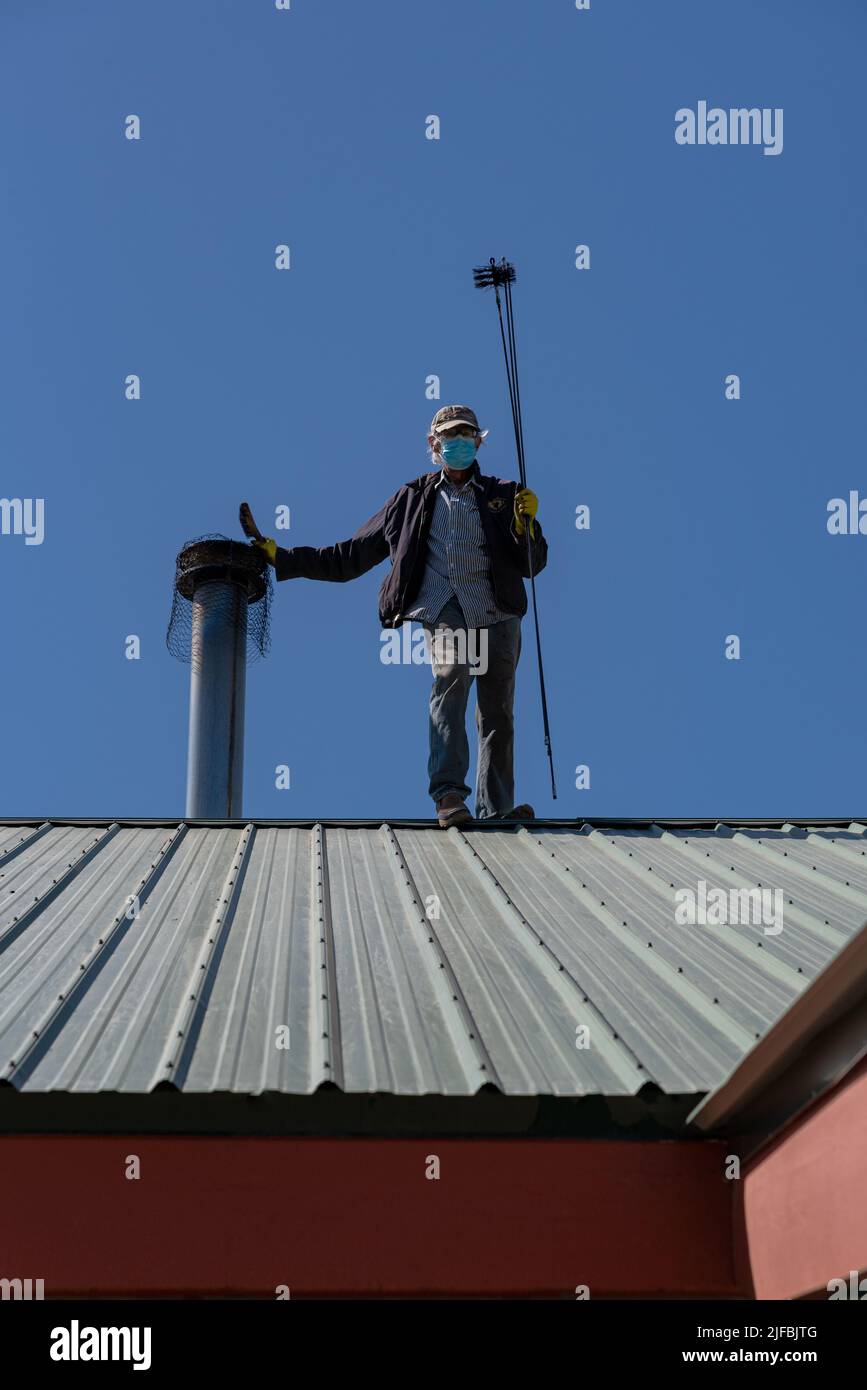A chimney sweep stands on the roof of a house Stock Photo - Alamy