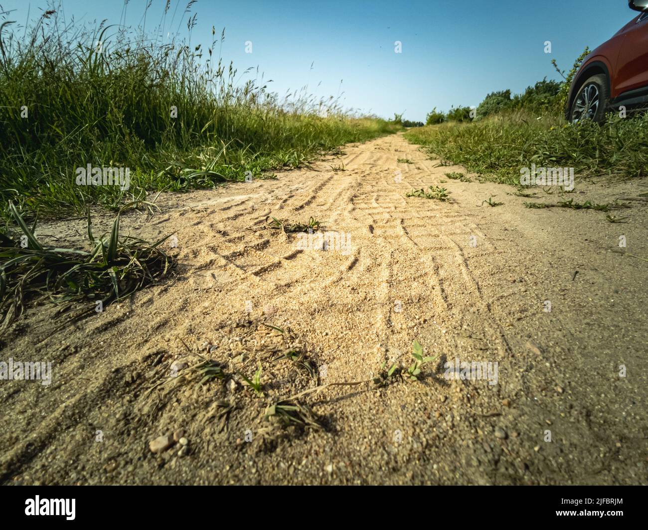 Empty dirt road through the meadow. Footprints in the sand Stock Photo ...
