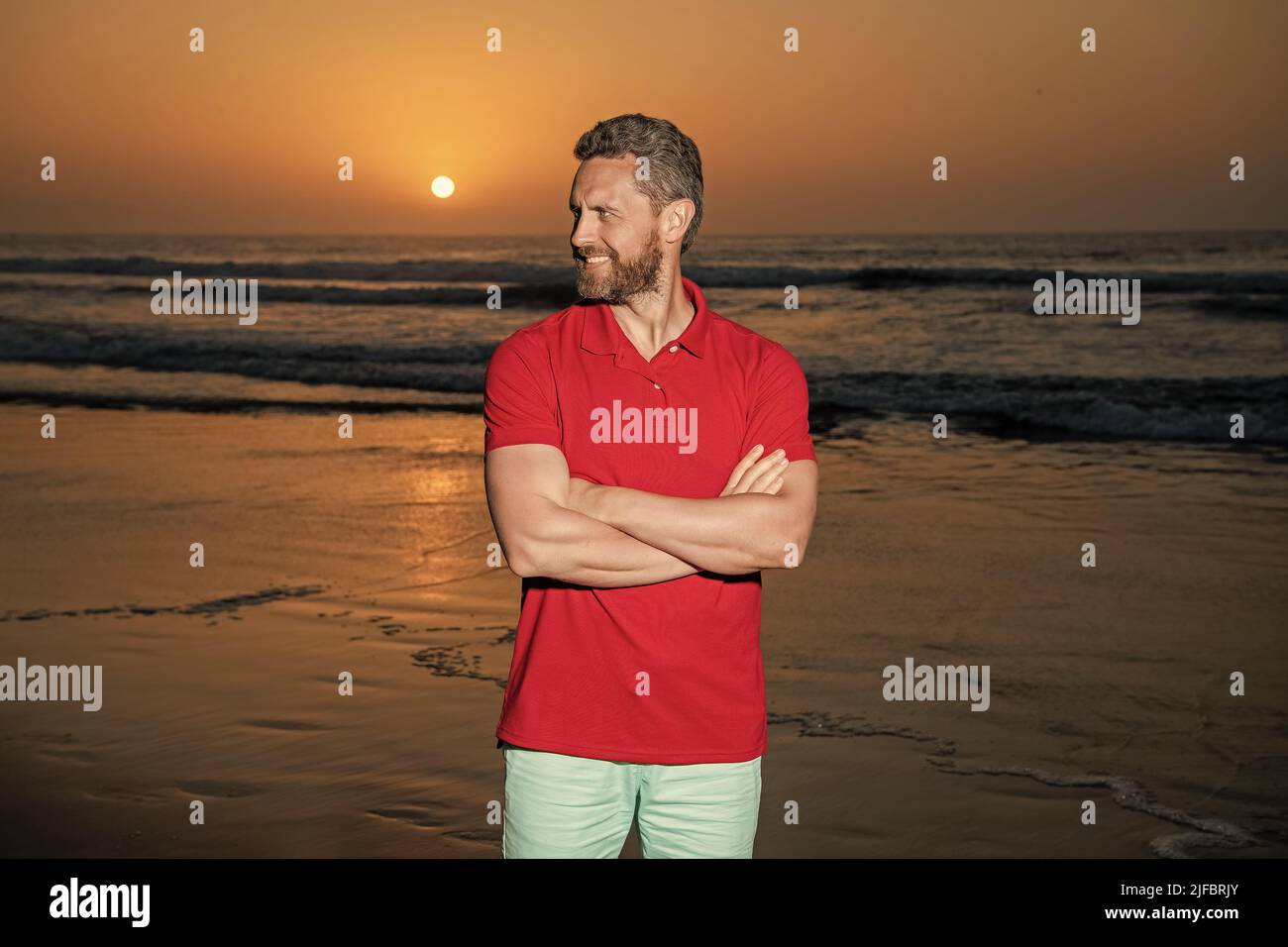 cheerful man with beard in sunset over sea. unshaven guy on beach ...