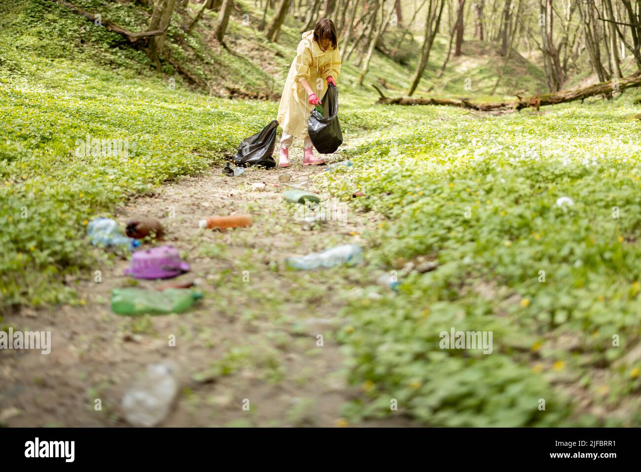 Woman collecting scattered plastic garbage in the woods Stock Photo - Alamy