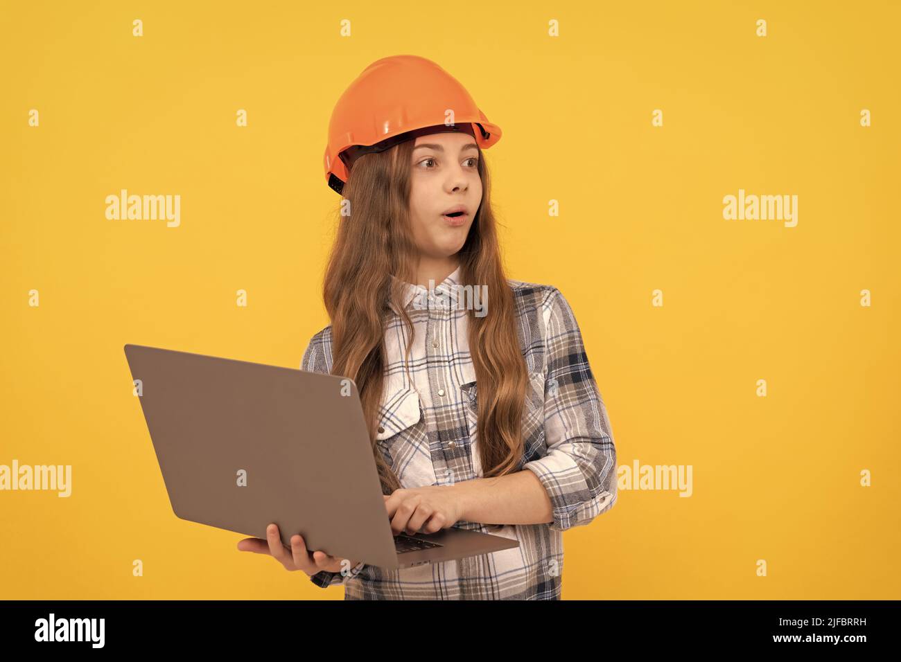 surprised teen girl in helmet and checkered shirt using computer ...