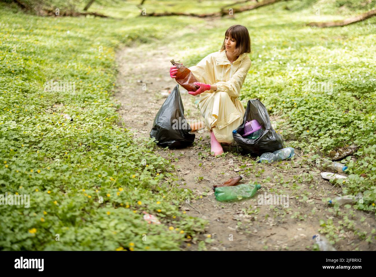Woman collecting scattered plastic garbage in the woods Stock Photo - Alamy