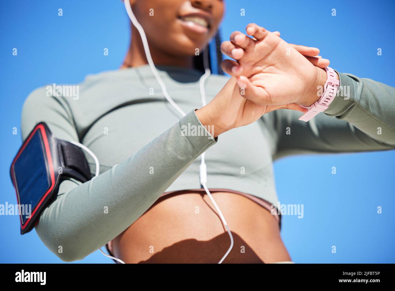 Fit african american woman checking her smartwatch, timing her progress ...