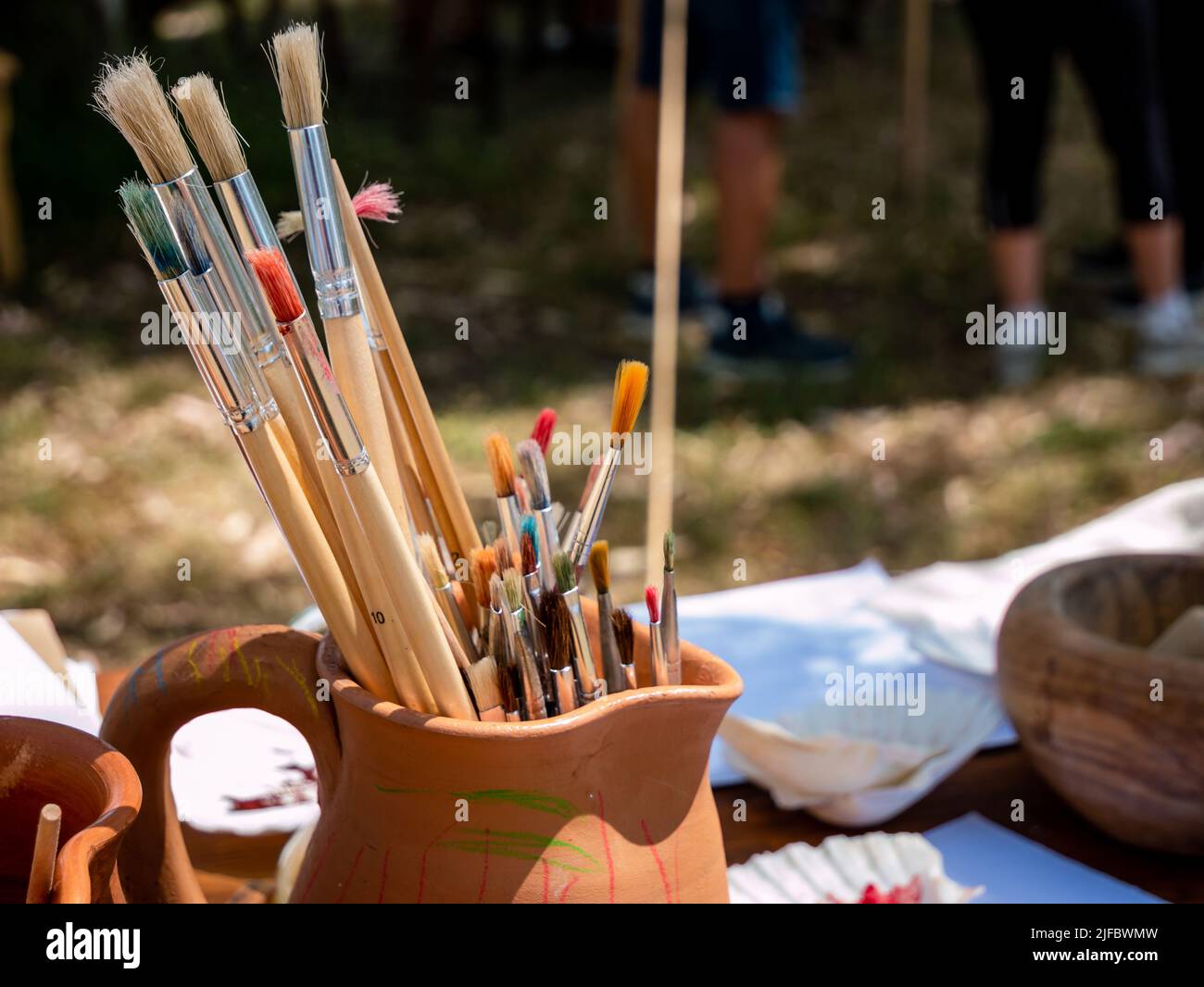 paint brushes in a ceramic jug, medieval painter's equipment on a table ...