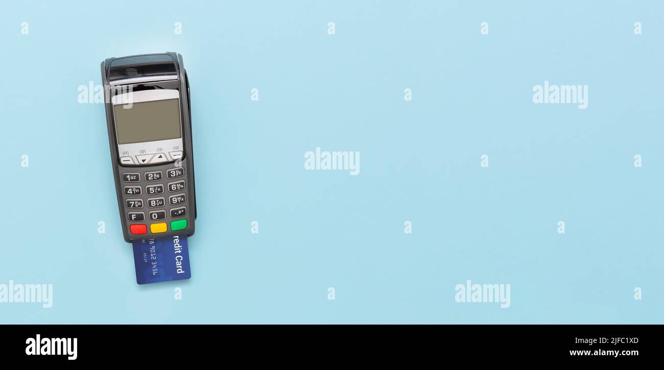 Payment terminal with credit card on blue background with copy space ...