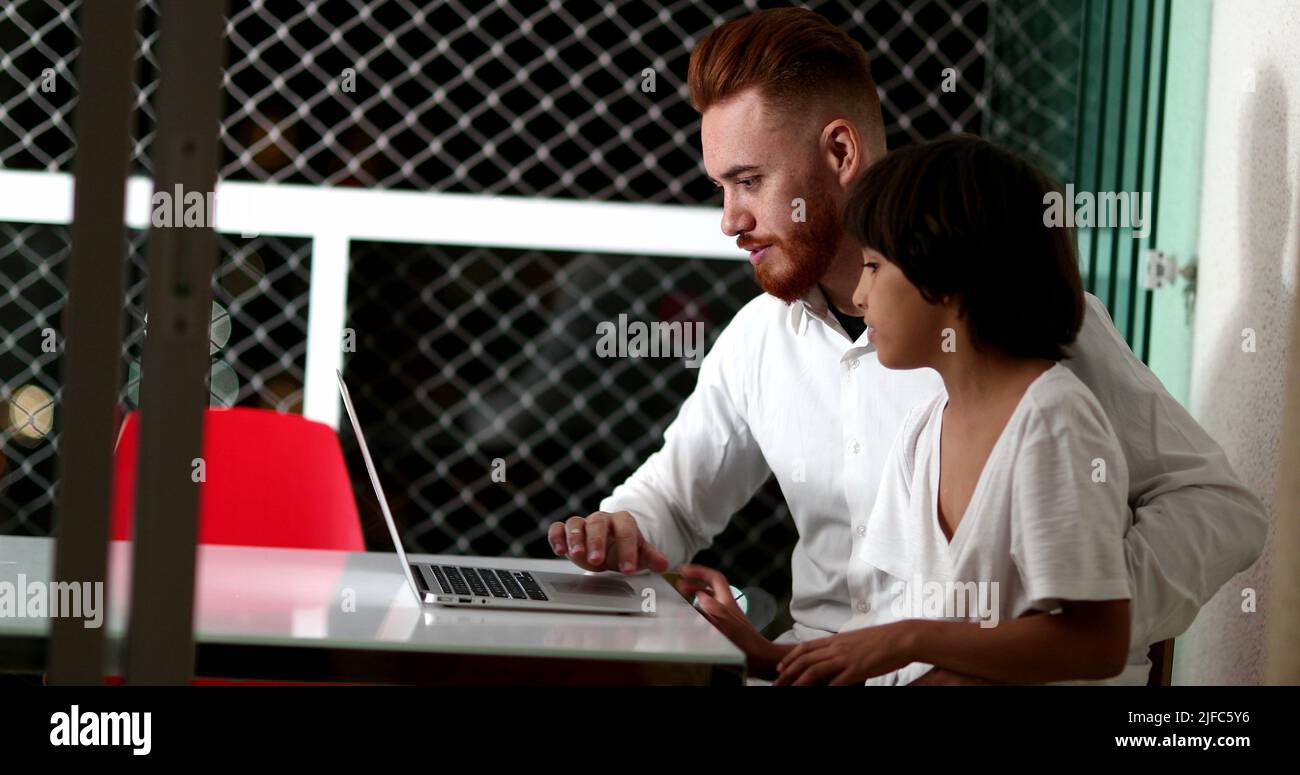Father and son together using laptop. White dad with mixed race child ...