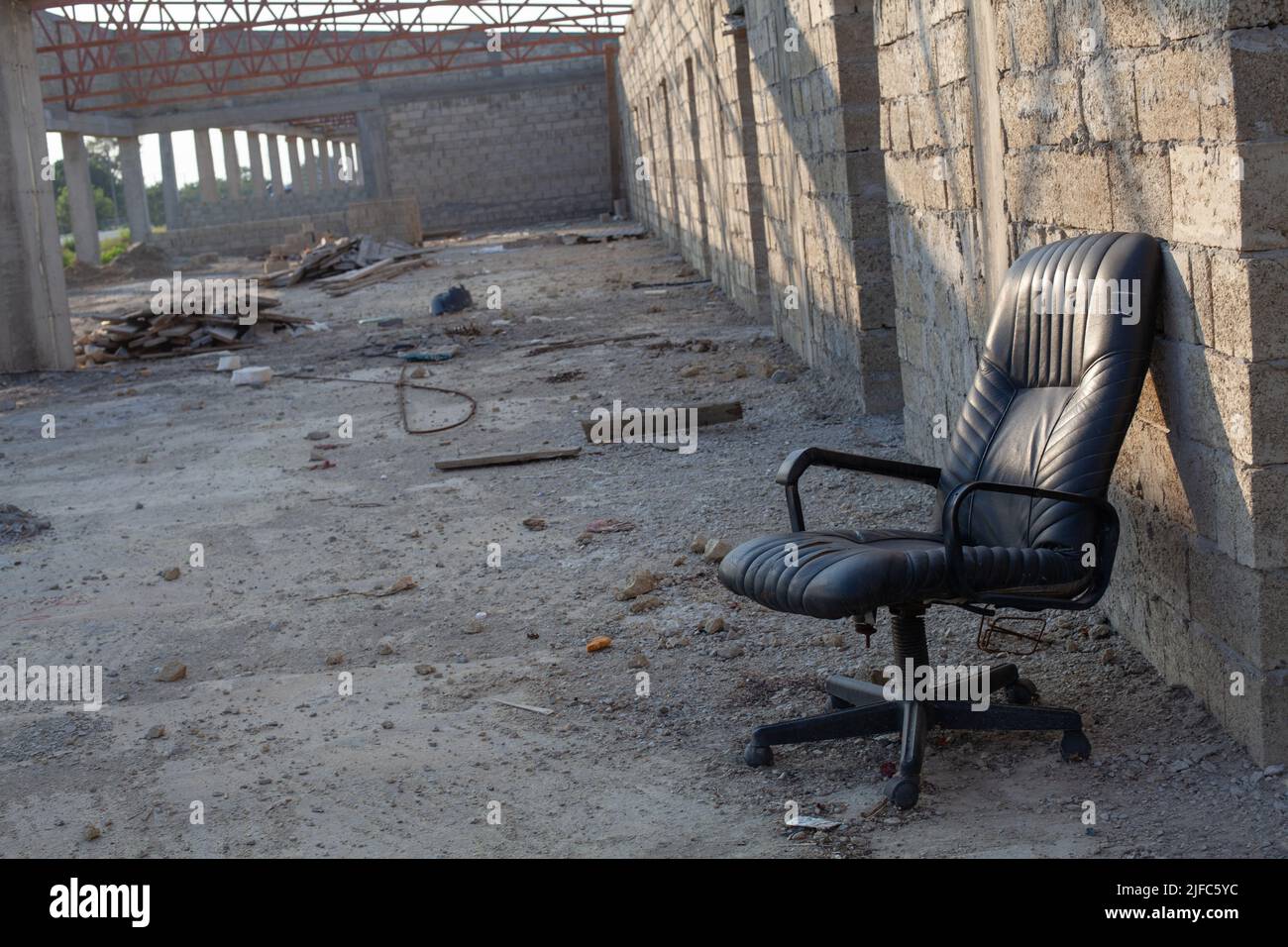Building construction. Old black chair on grunge brick wall background ...