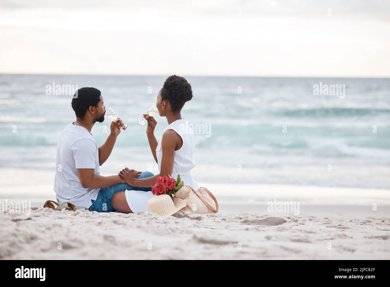Young african american couple drinking champagne at the sea together ...