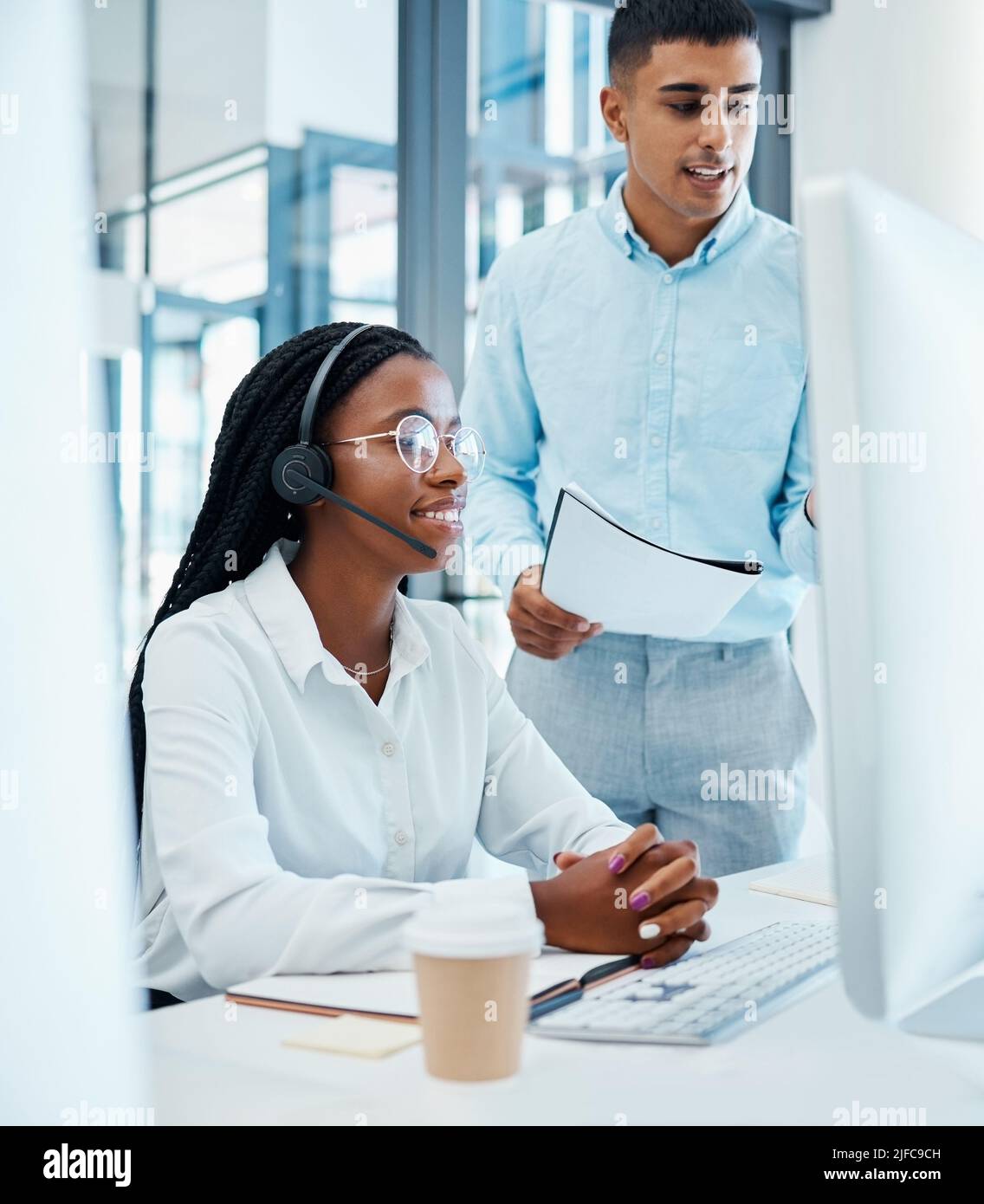 Call center manager discussing clients with a help desk operator waring ...