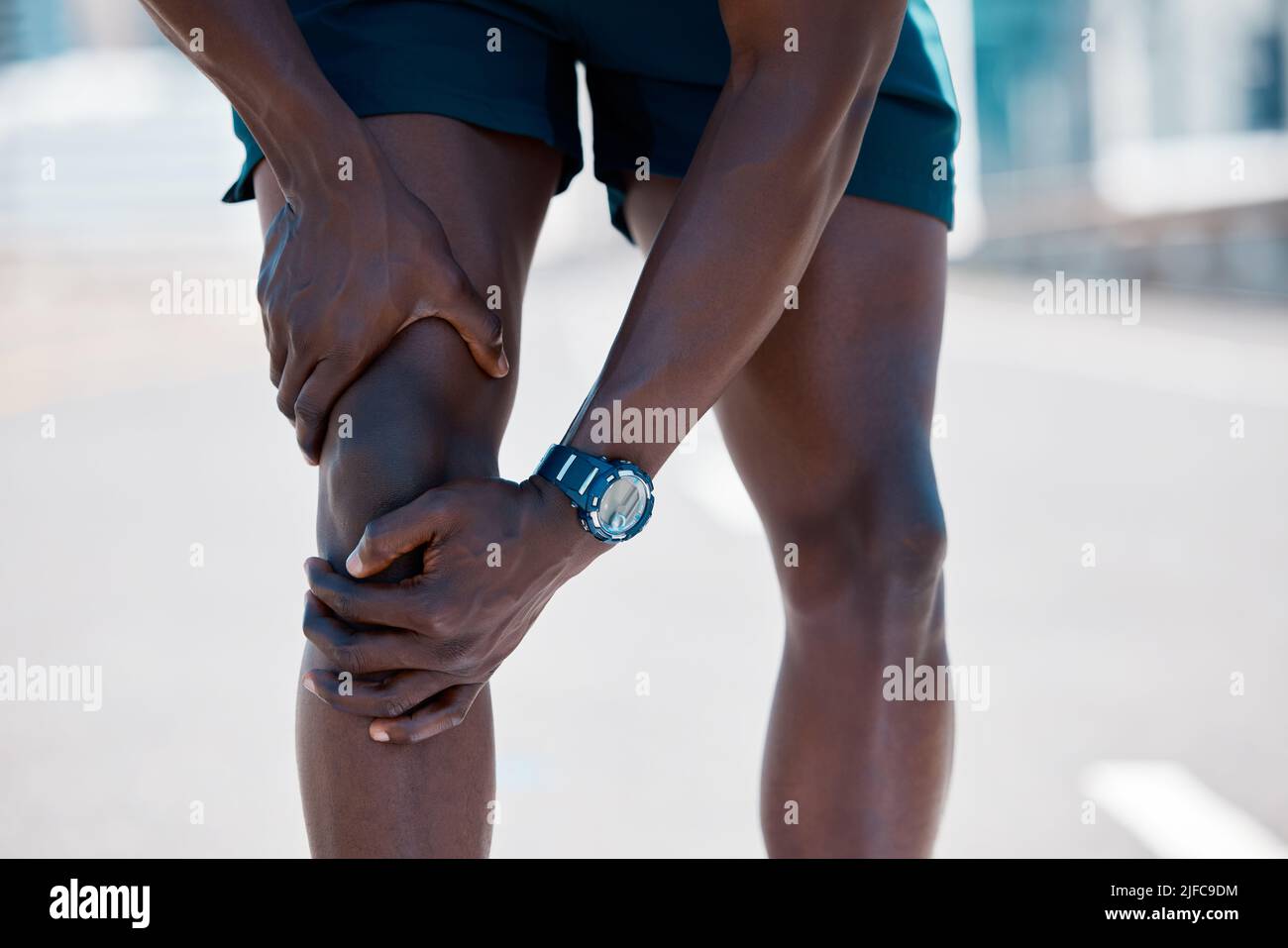 African american athlete taking a break from running to touch his knee ...