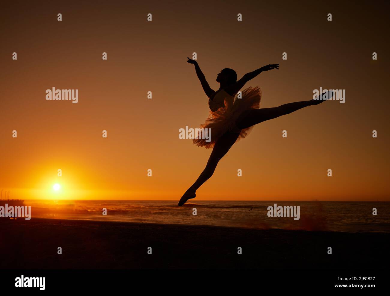 Silhouette of a ballet dancer in tutu dancing on the beach at sunset ...