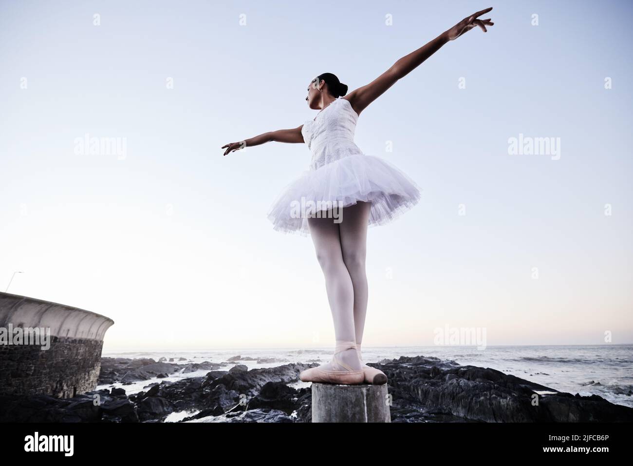 Young ballerina standing with her arms outstretched while practising ...