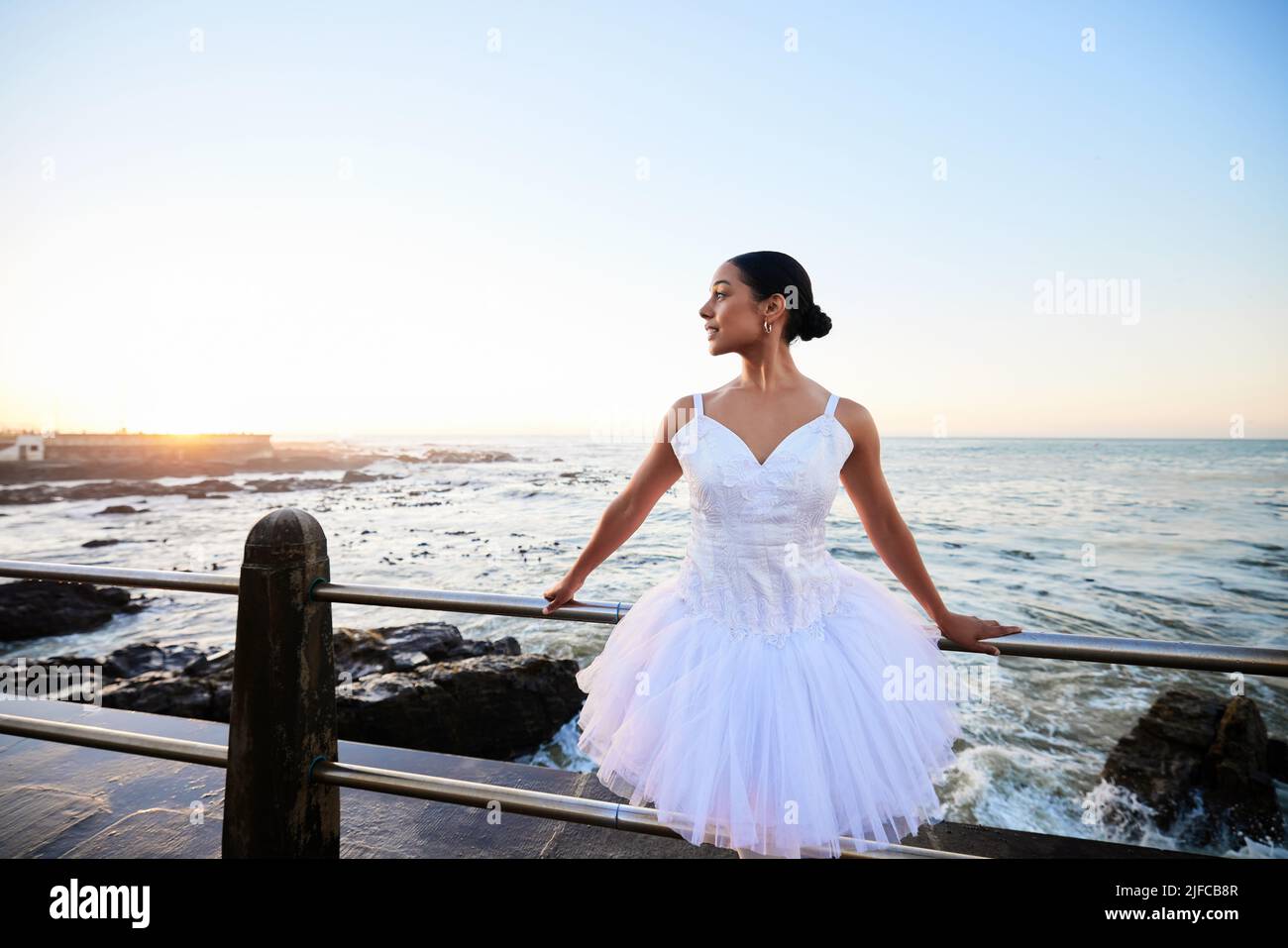 Elegant young ballerina wearing white fancy dress while leaning against ...