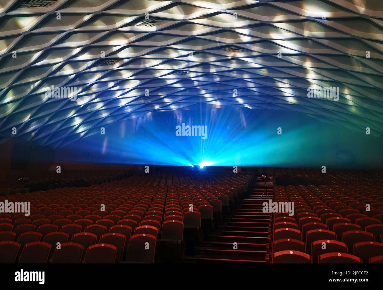 An empty cinema hall with red chairs and blue lights lightning the ...