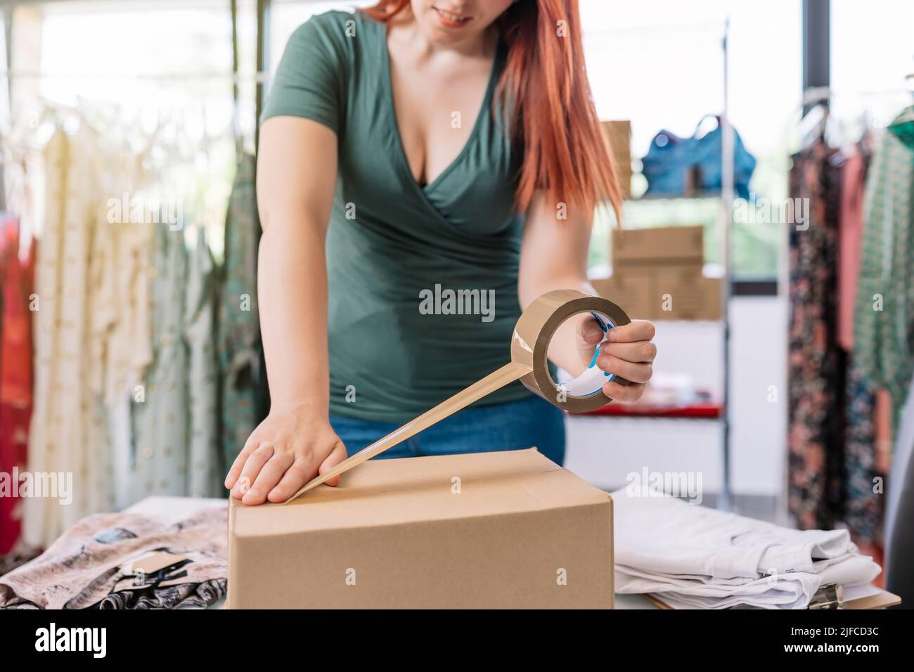Cutaway view of a young businesswoman, packing a box with tape, for a ...