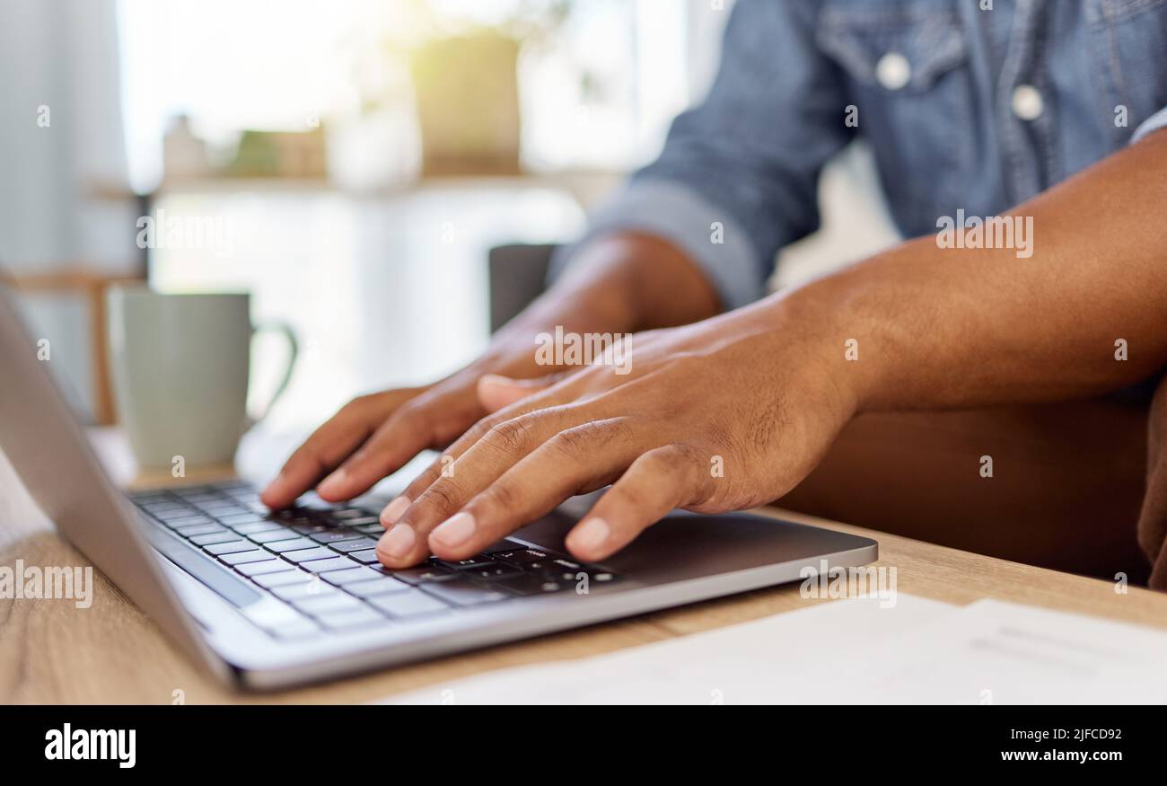 Closeup of a mans hand typing an email while working on a laptop alone ...