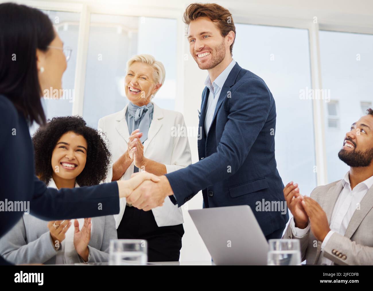 Smiling young businessman shaking hands with a businesswoman during a ...
