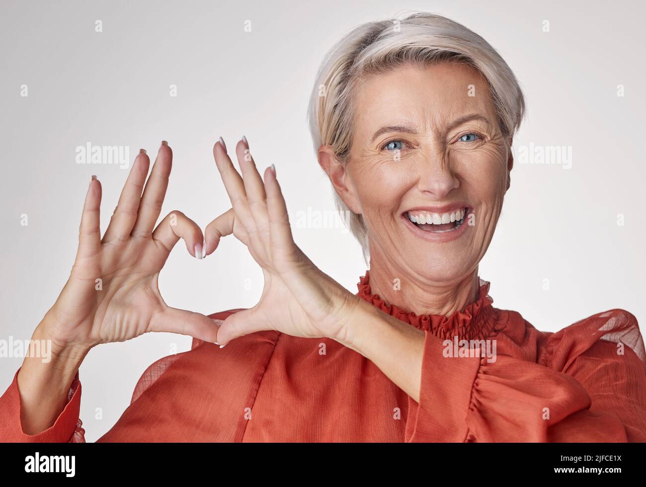 One happy mature caucasian woman showing a heart shape with her hands ...