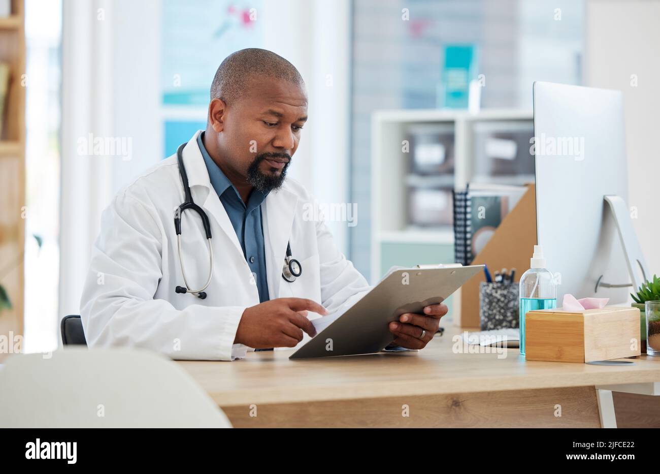 Mature african american doctor checking a patients chart. Focused gp ...